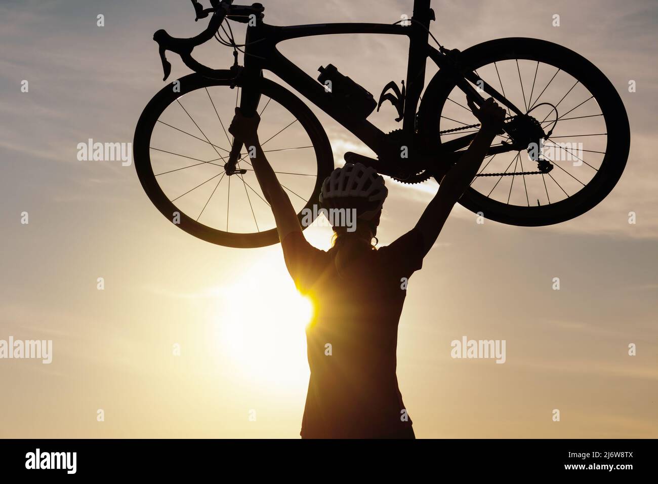 Female road cyclist raising bicycle with both arms above her head at ...