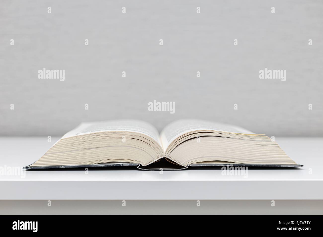 a thick book in an open form lies on a white table. High quality photo ...