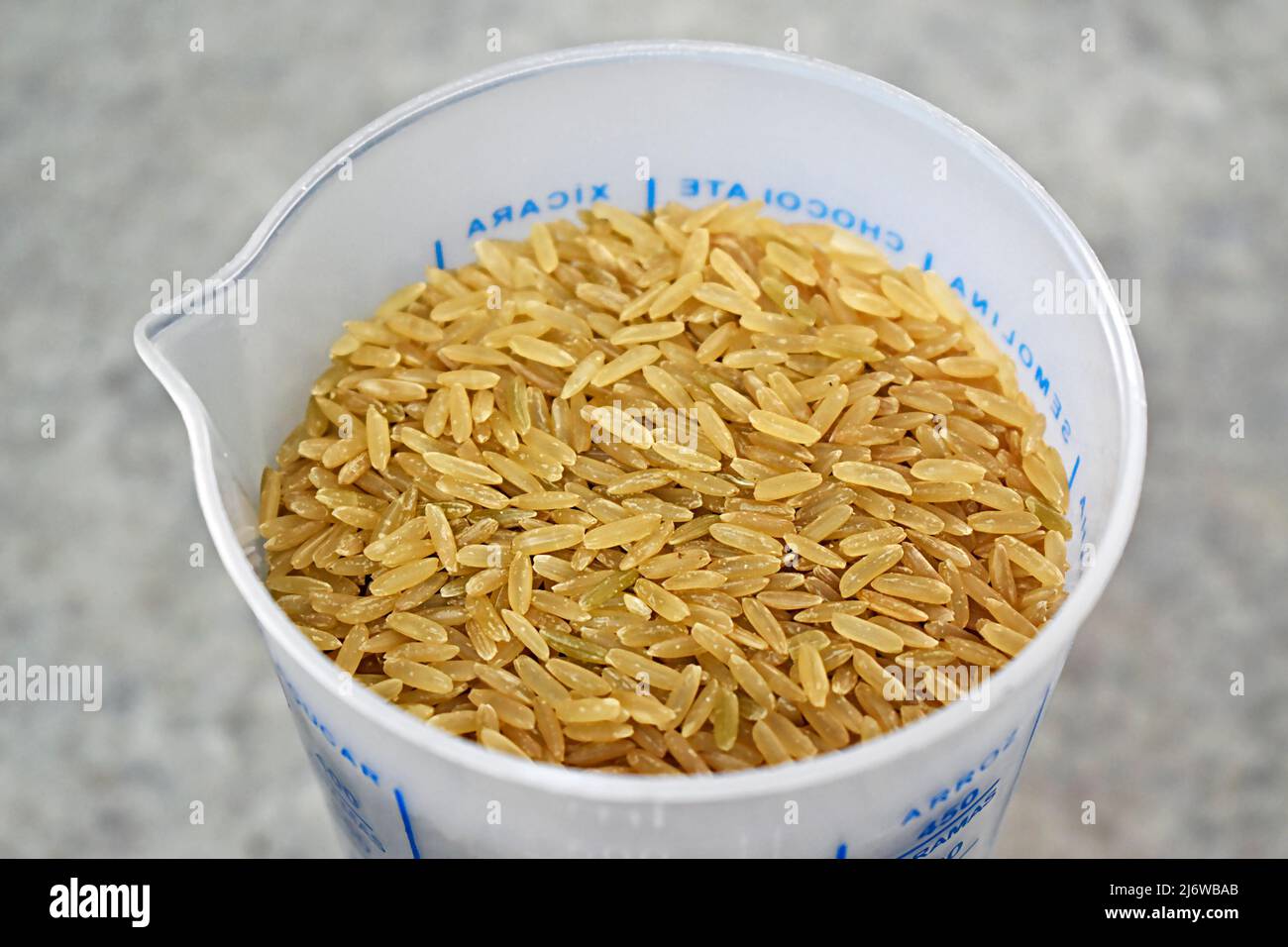 Brown rice grains on measuring cup in the kitchen Stock Photo - Alamy