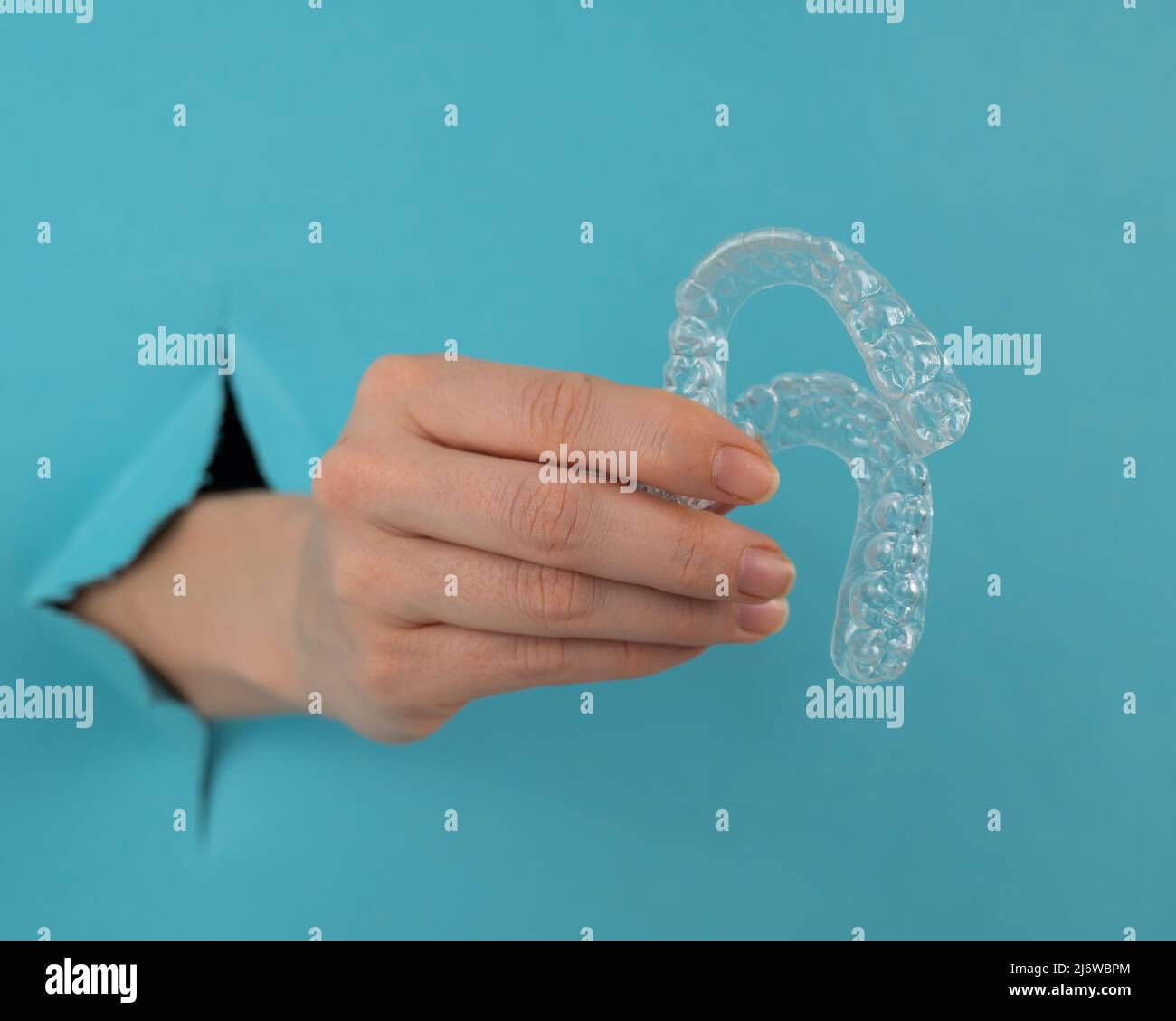 A female hand sticking out of a hole from a blue background holds ...