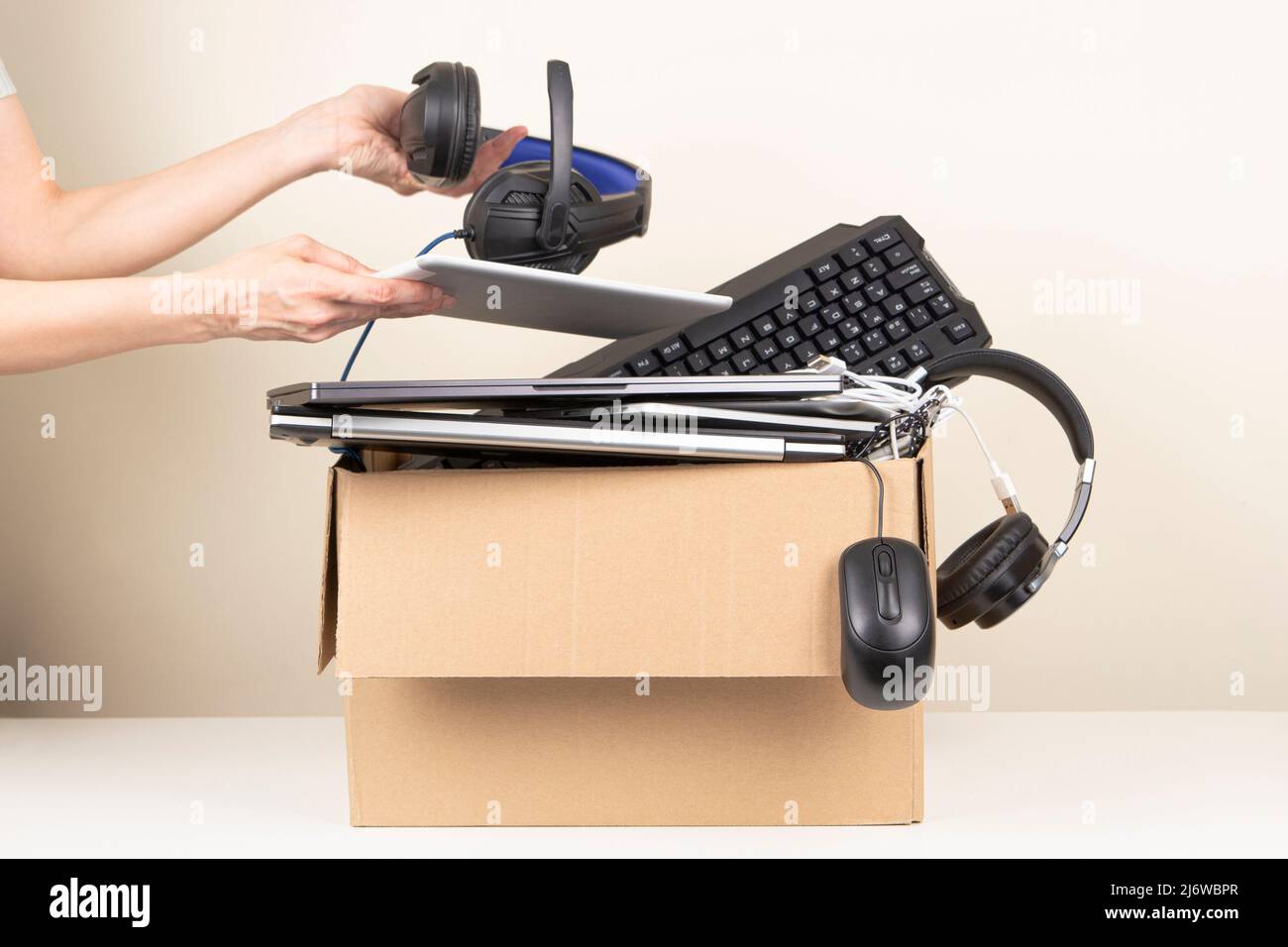 Woman hands put laptop computer and headphones in box full old used ...