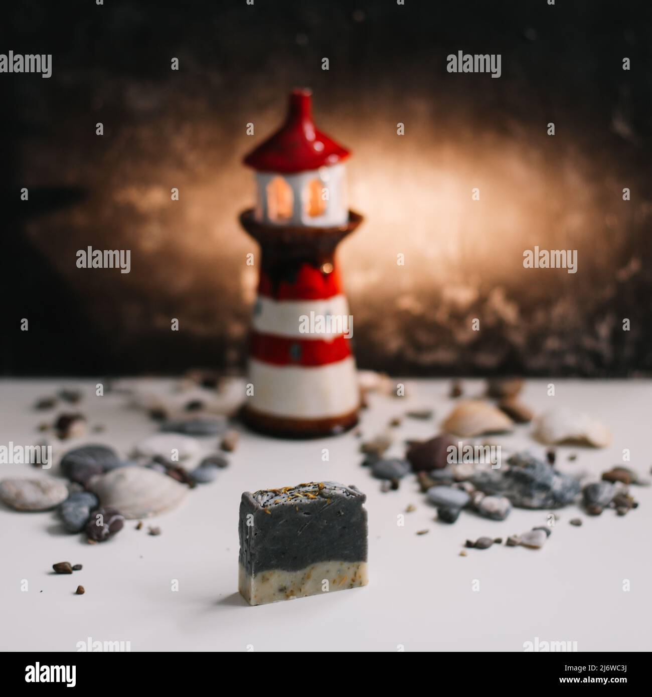 A small decorative lighthouse with sea shells and stones on a dark ...