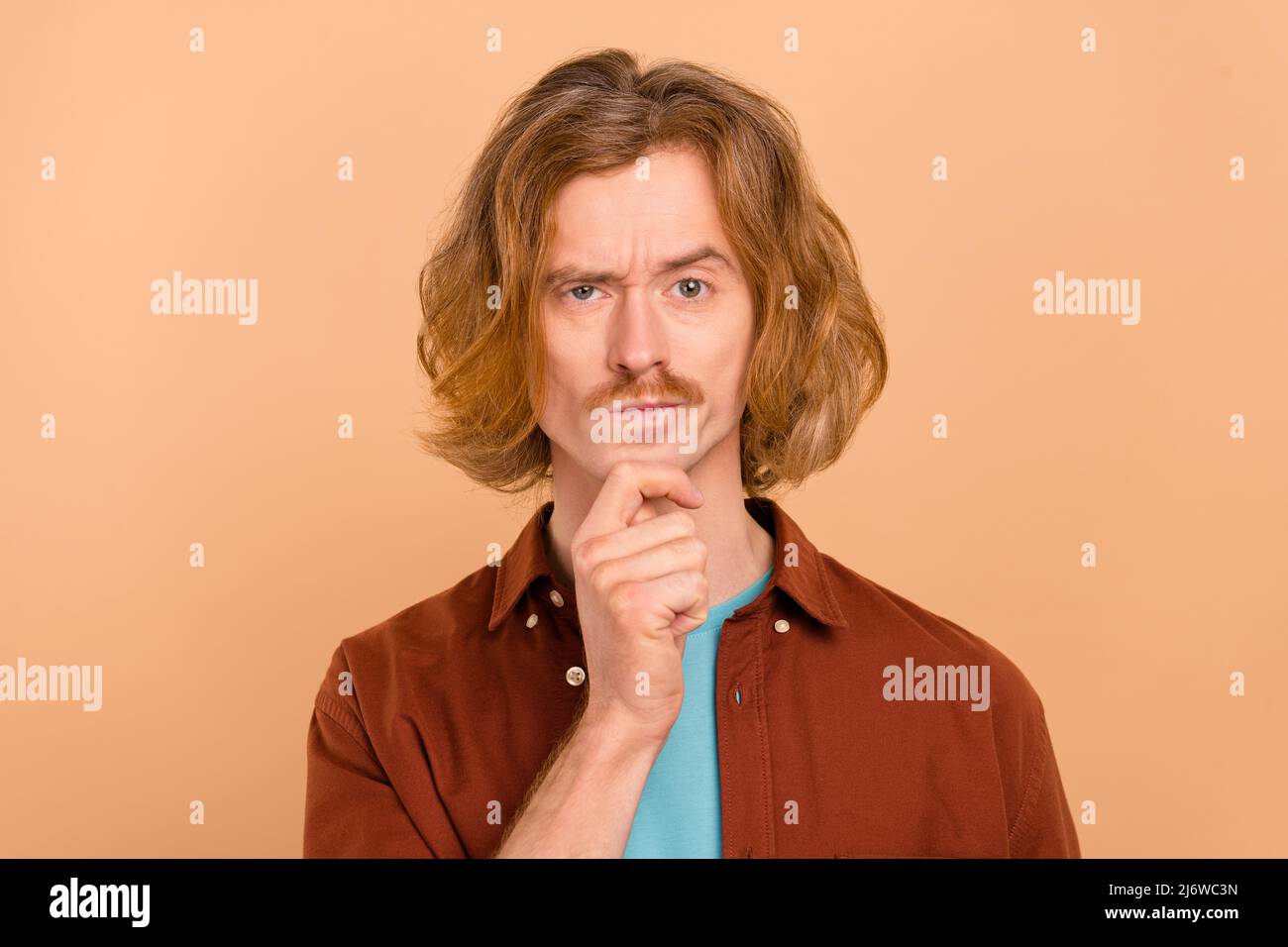 Portrait of attractive unsure bewildered red-haired guy touching chin ...