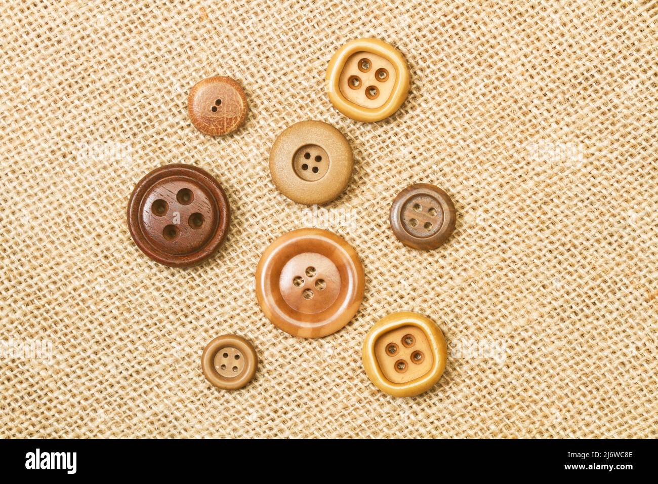 Brown sewing buttons on a burlap fabric in a top view Stock Photo - Alamy