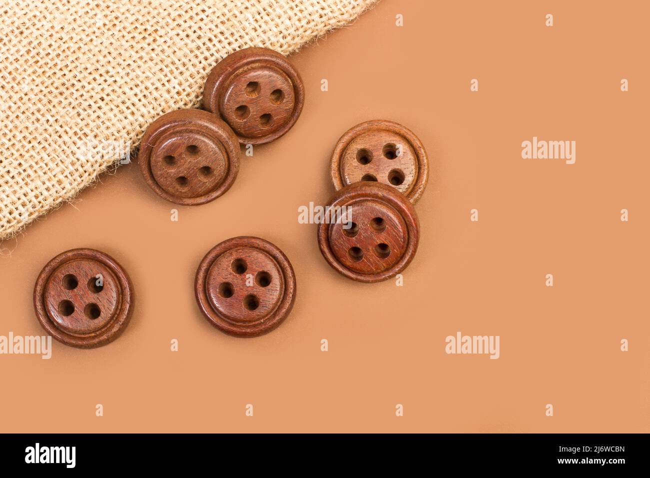 Brown sewing buttons on a burlap fabric and on a brown background with ...
