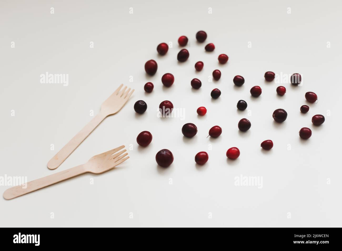wood fork, bamboo cutlery and berries on white background, zero waste, no plastic, eco-friendly ...