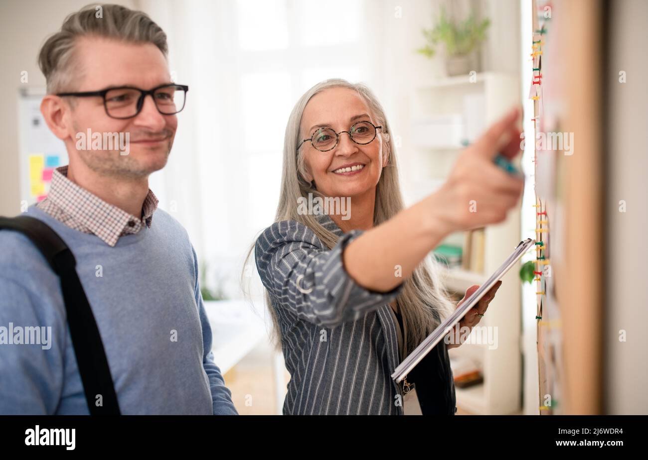 Recrutiment agency employee standing in front of employment noticeboard ...