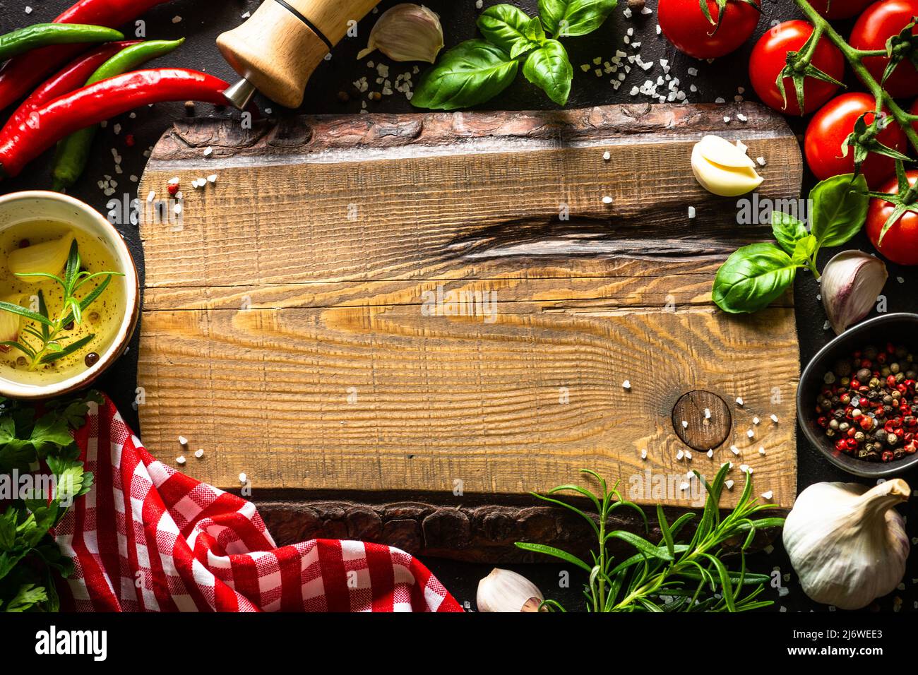 Food background. Oak cutting board, spices and vegetables at kitchen ...