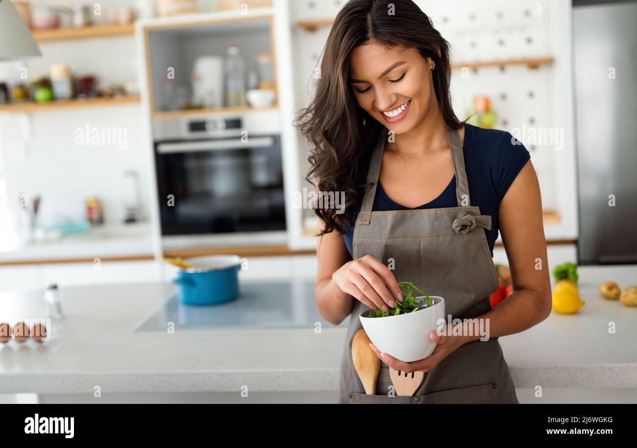 Woman making salad in kitchen smiling and laughing happy and cheerful ...