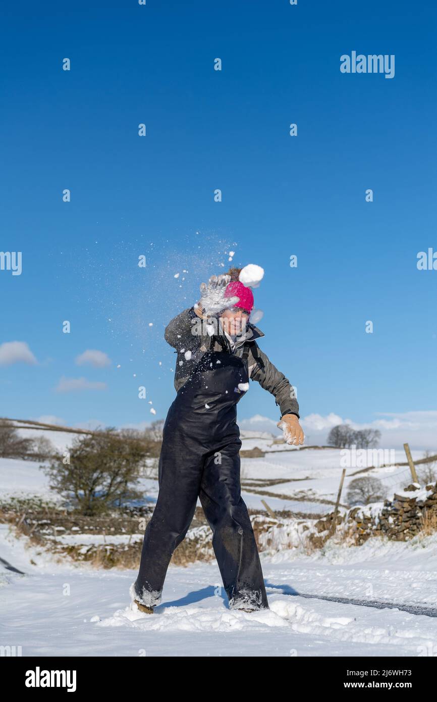 Woman throwing a snowball after a snow storm in Wensleydale, North ...