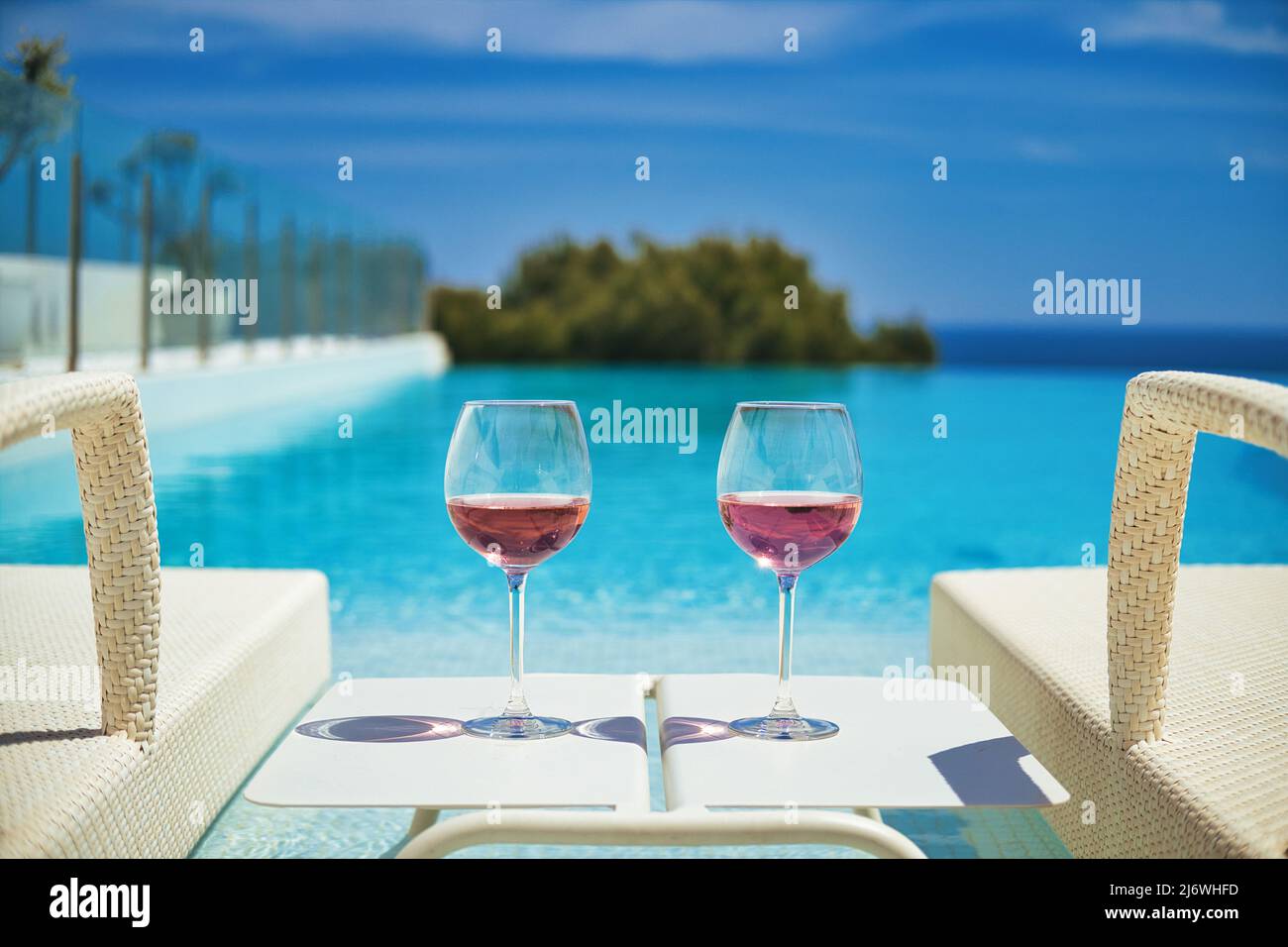 Two glasses with cocktails on table between deck chairs sunbeds on the ...