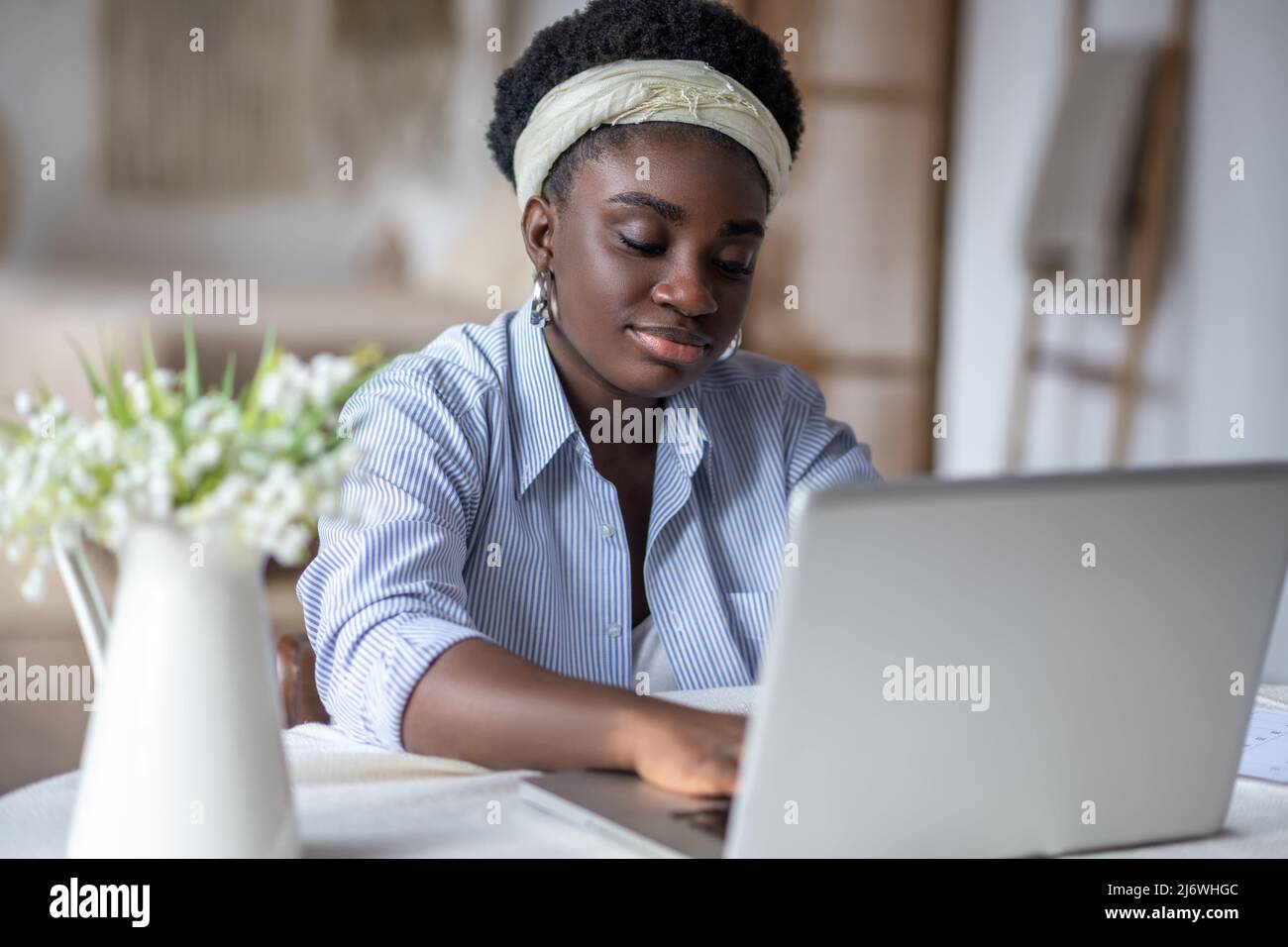 African american woman sitting at the table and working on a laptop ...
