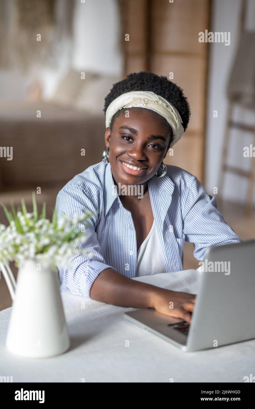 African american woman sitting at the table and working on a laptop ...