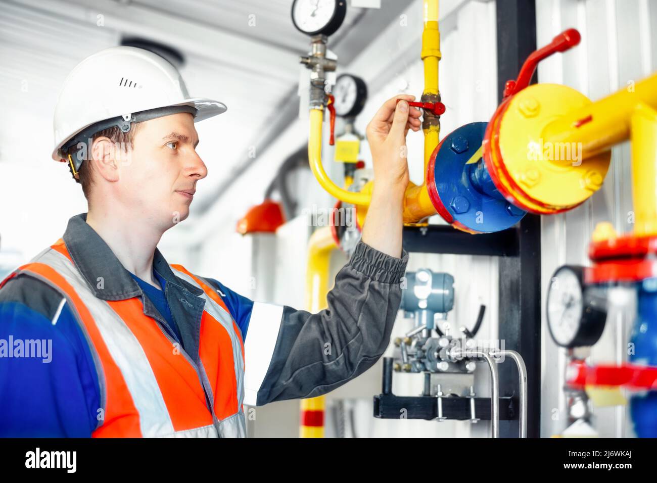 Engineer in white helmet and overalls shuts off natural gas supply tap ...