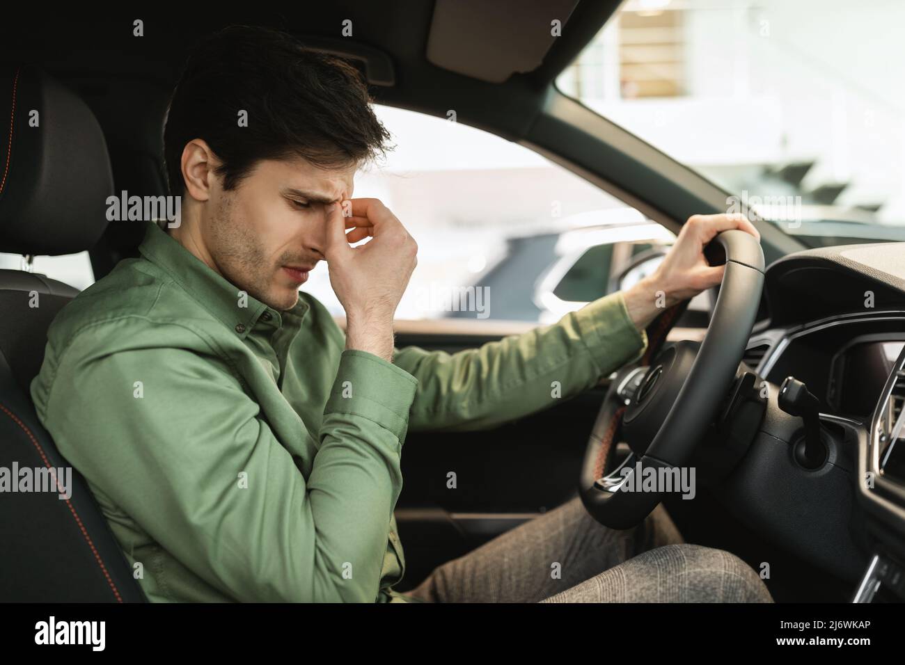 Unhappy young man sitting on driver's seat of new car, disappointed ...