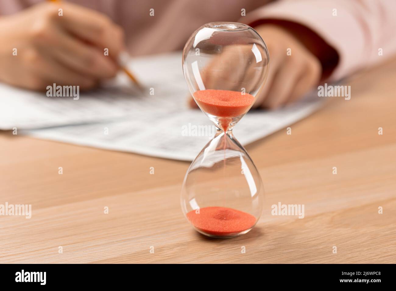 Hourglass with time running out and student hand testing in exercise ...