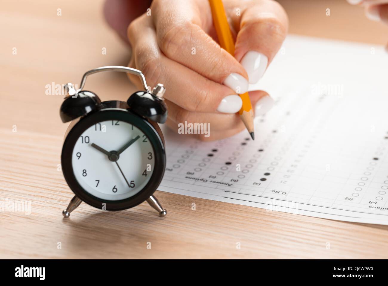 alarm clock with time running out. Students hands to take exams, write ...