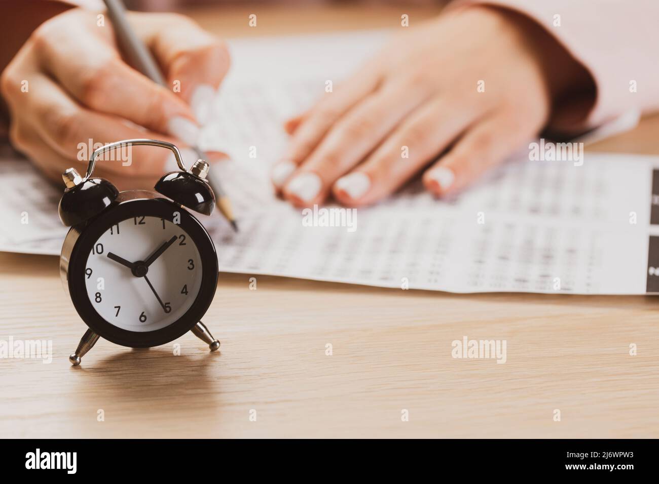 alarm clock with time running out. Students hands to take exams, write ...