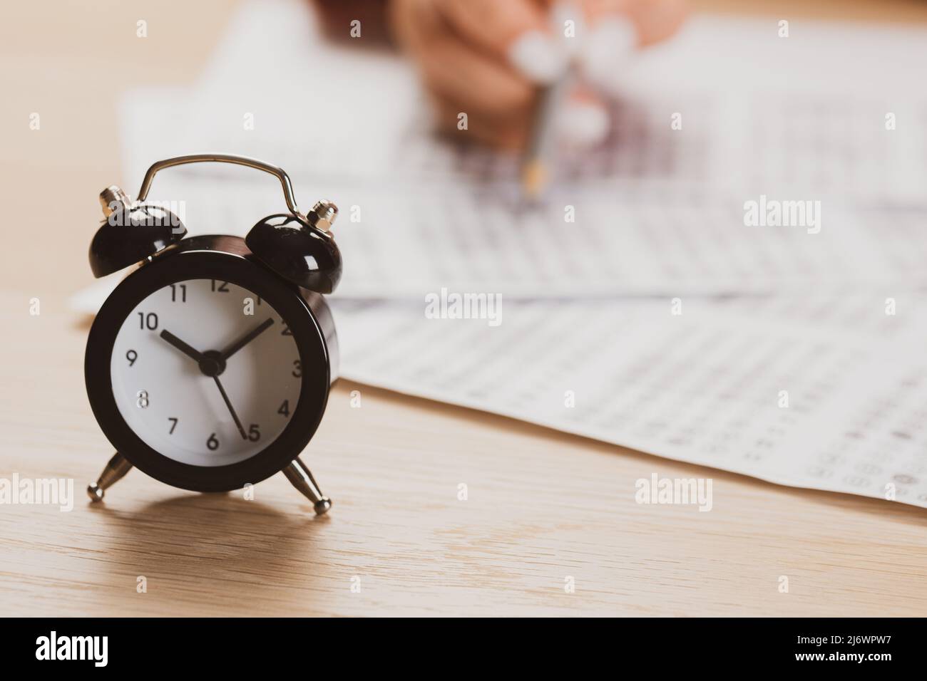 alarm clock with time running out. Students hands to take exams, write ...