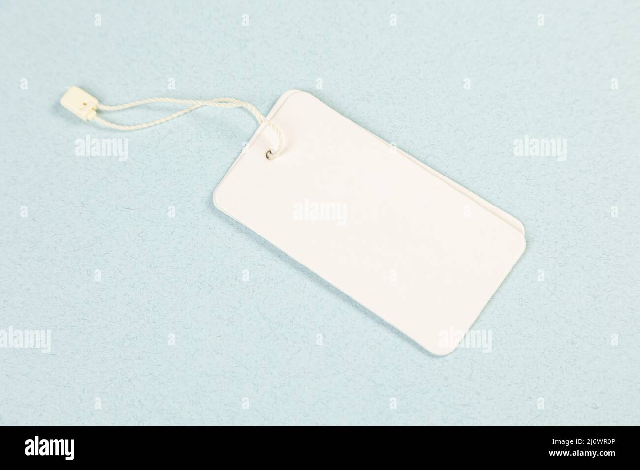 An empty white price tag lies on a gray-blue background with a soft ...