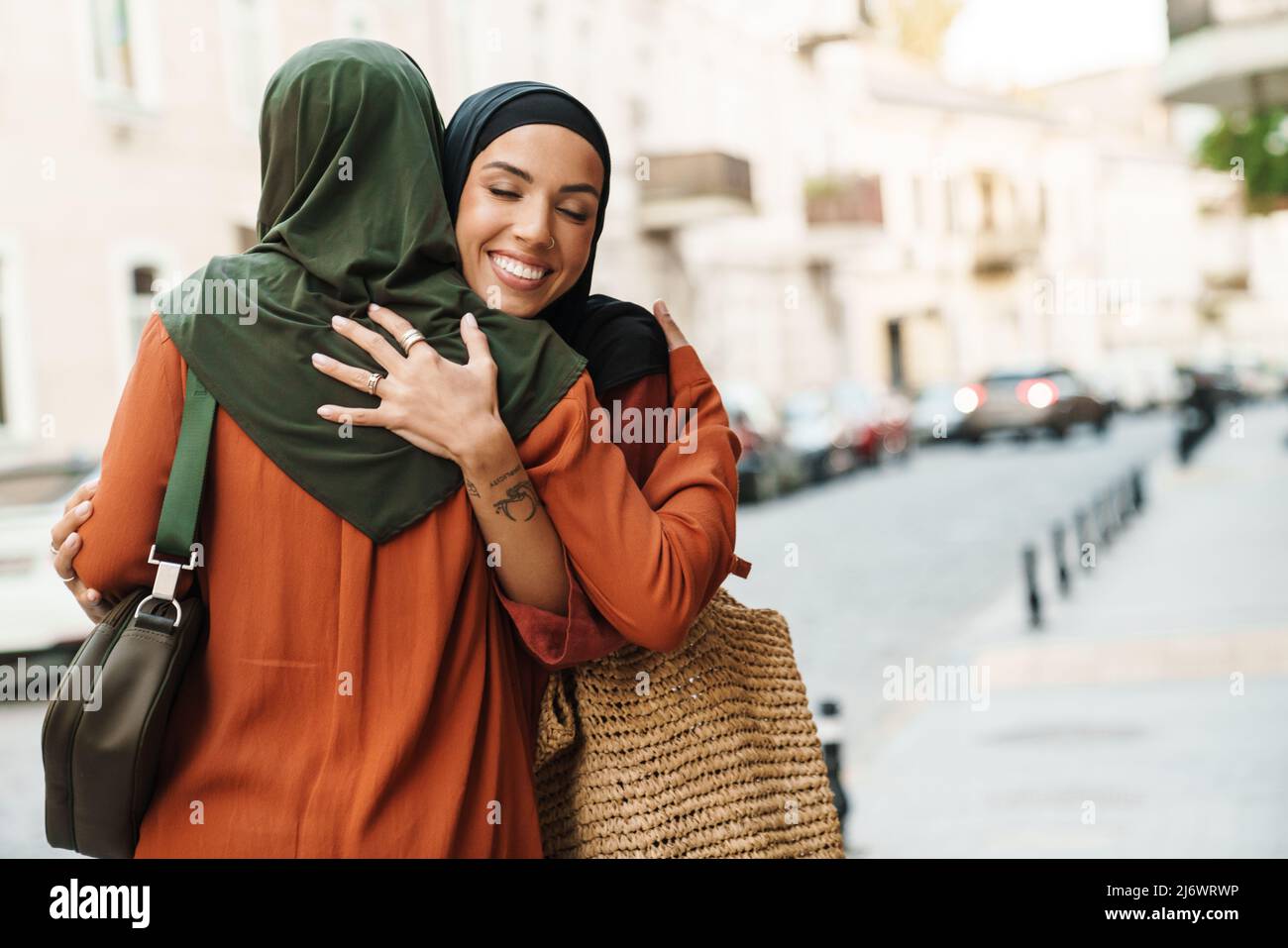 Multiracial muslim women smiling and hugging during meeting on city ...