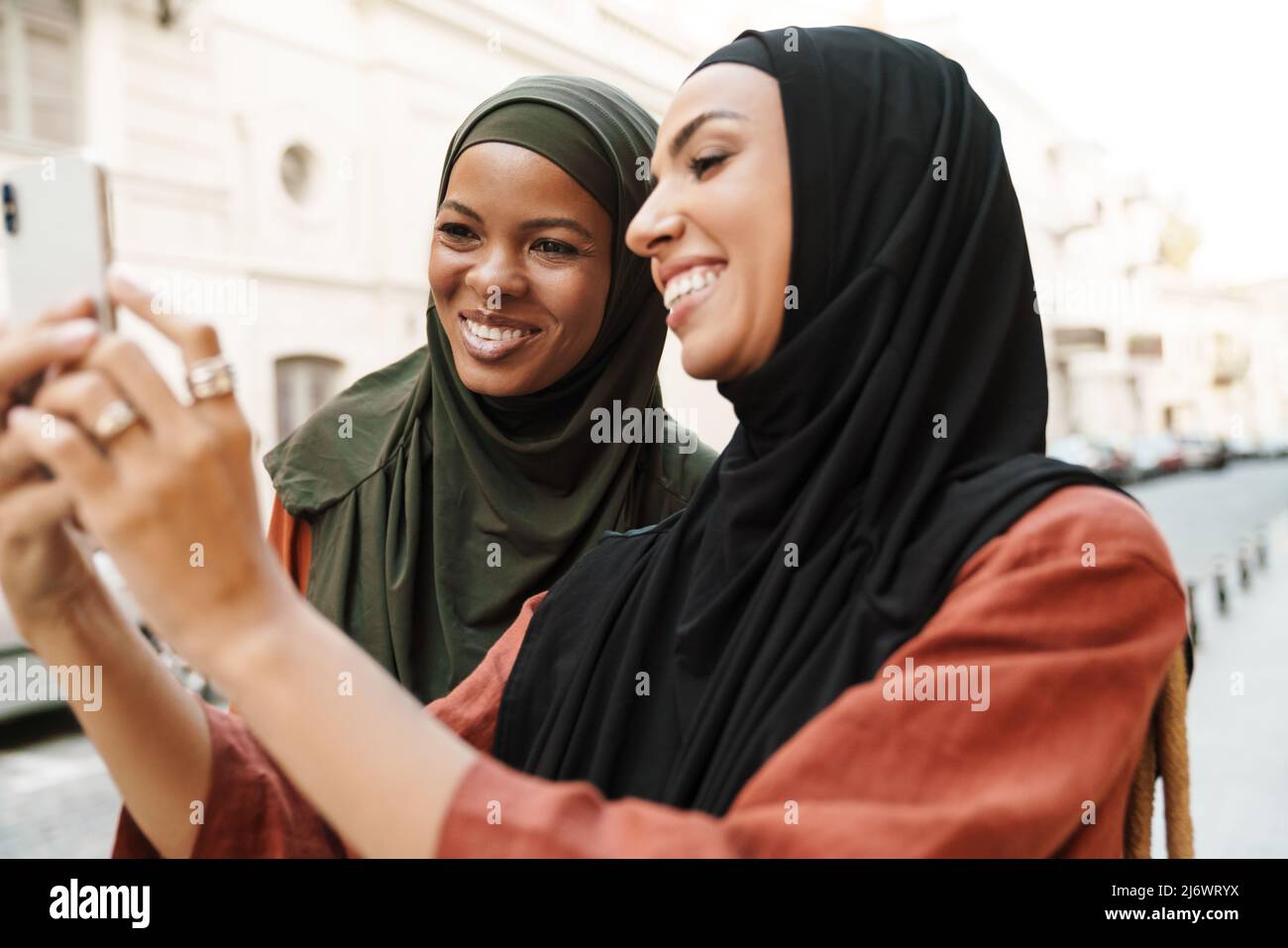 Multiracial muslim women using mobile phone during walking on city ...