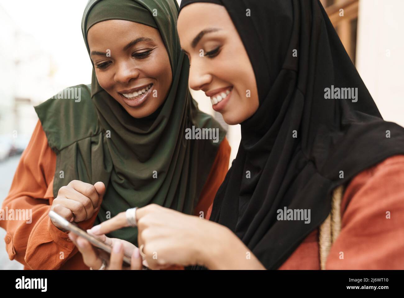 Multiracial muslim women using mobile phone during walking on city ...