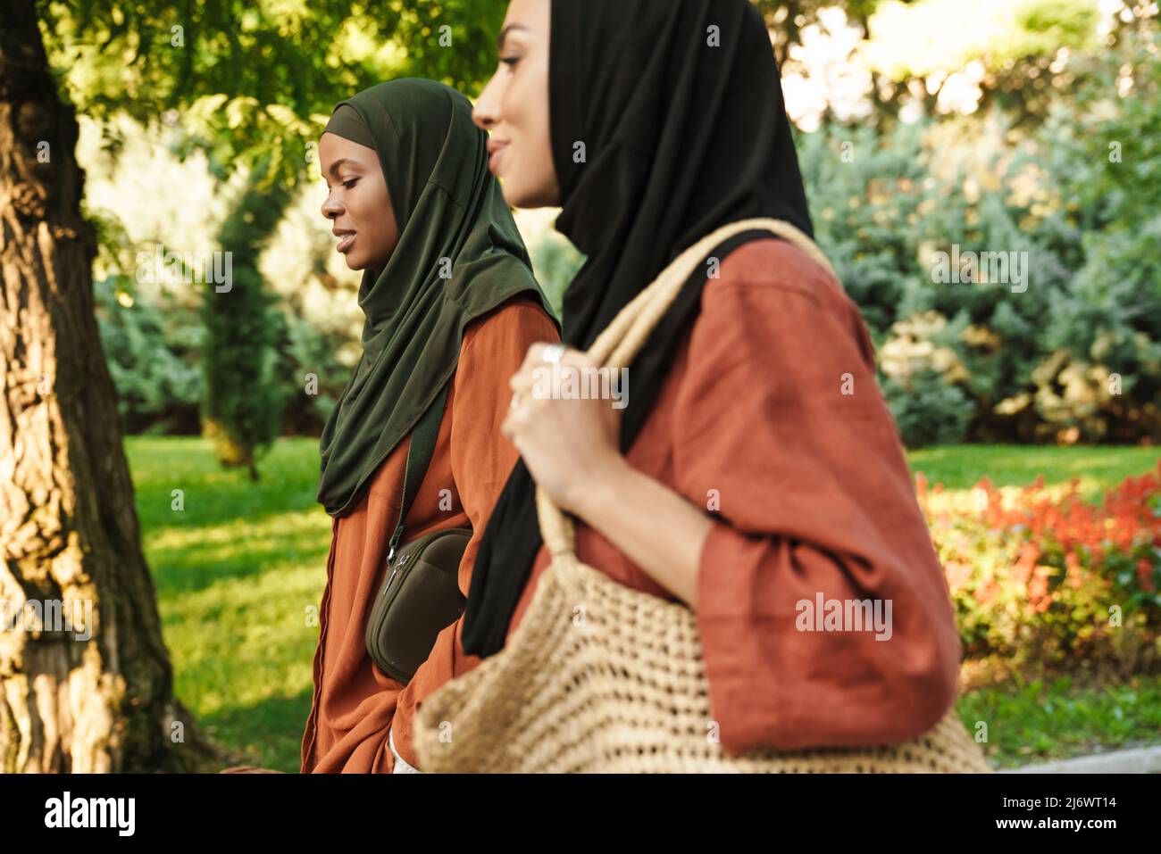 Multiracial muslim women dressed in hijabs talking during walking at ...