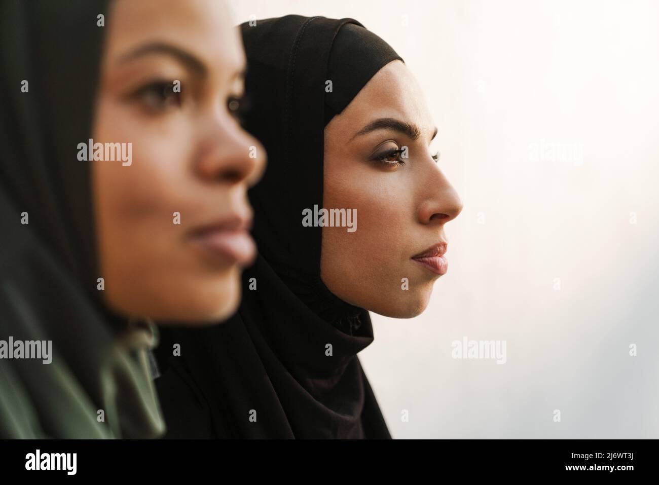 Multiracial muslim women posing and looking aside together outdoors ...
