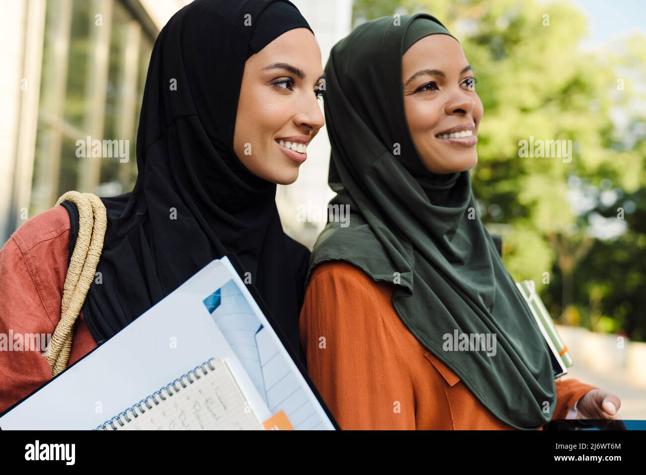 Multiracial muslim two women smiling together while standing outdoors ...