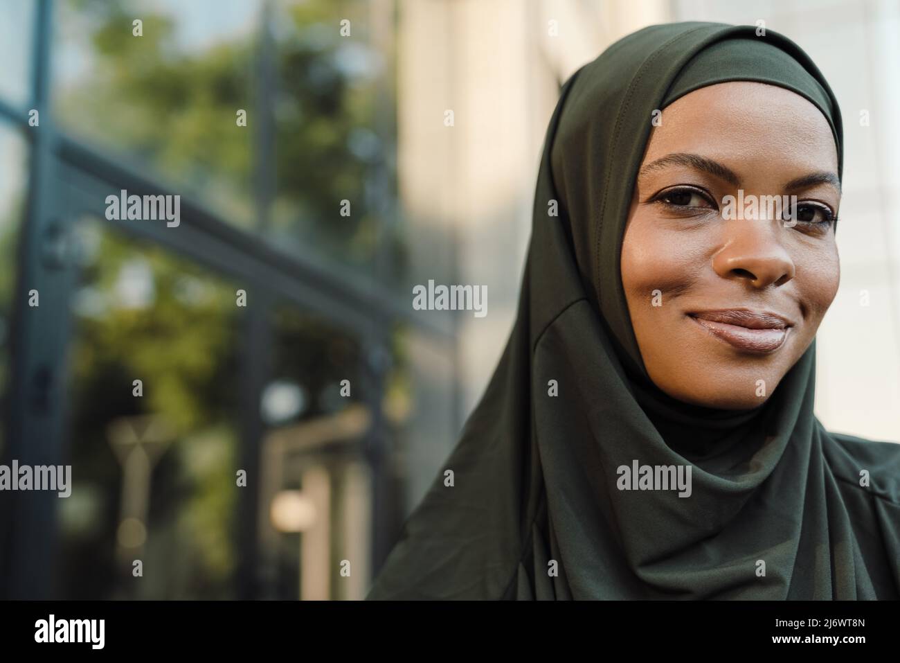 Black muslim woman dressed in hijab smiling and looking at camera ...