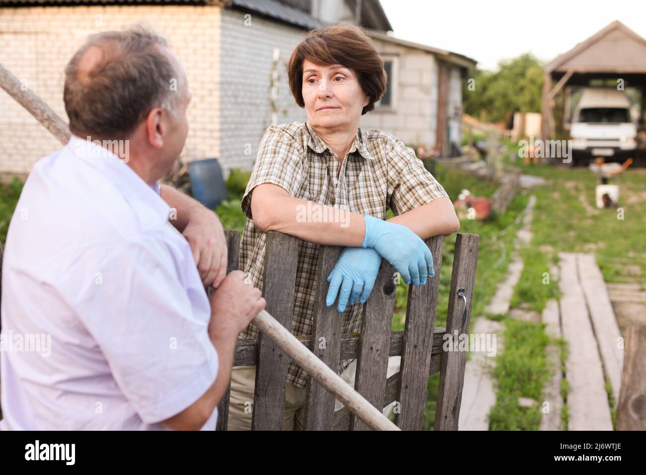 Farm neighbors talking at the fence Stock Photo - Alamy