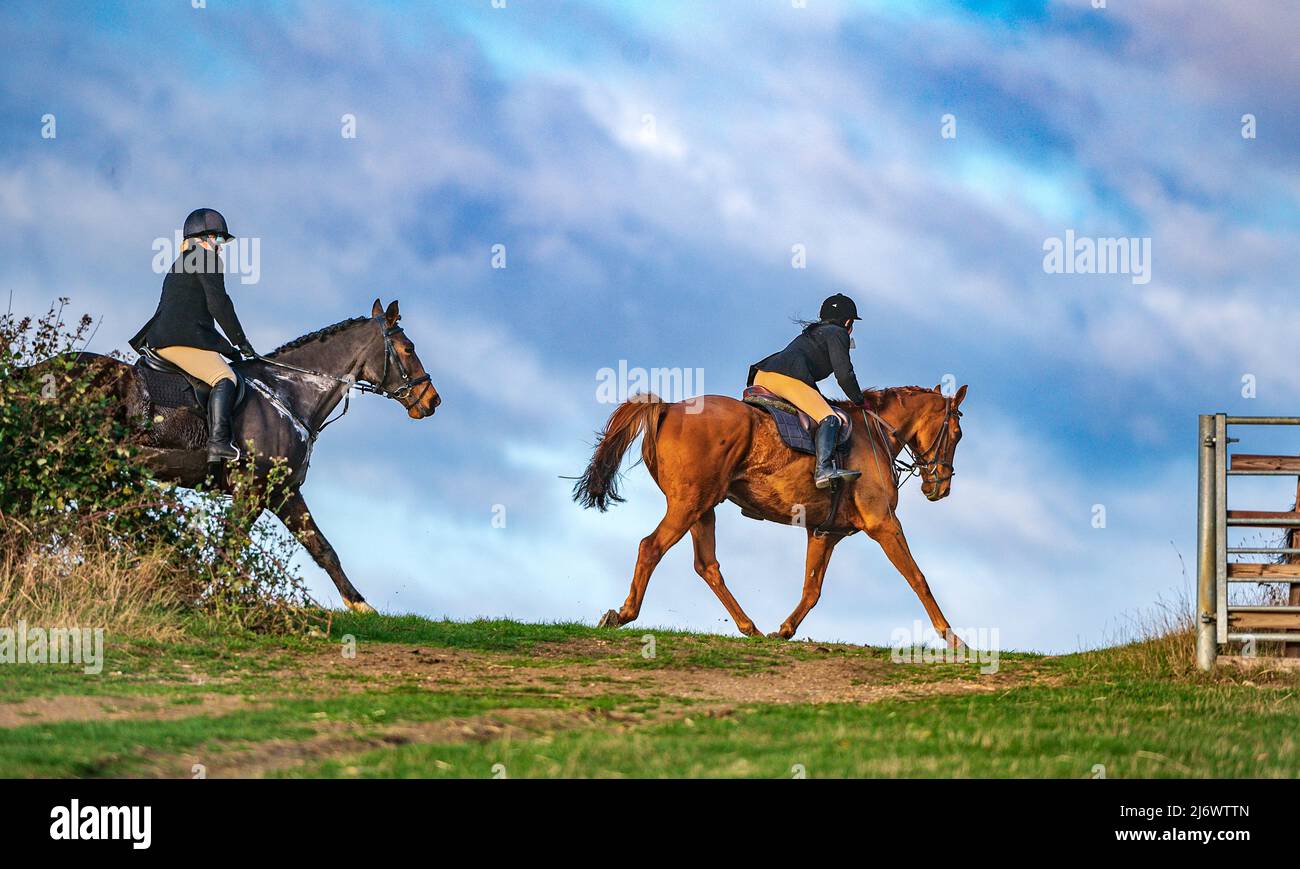 Horse riders galloping across the skyline on a horse against a stormy ...