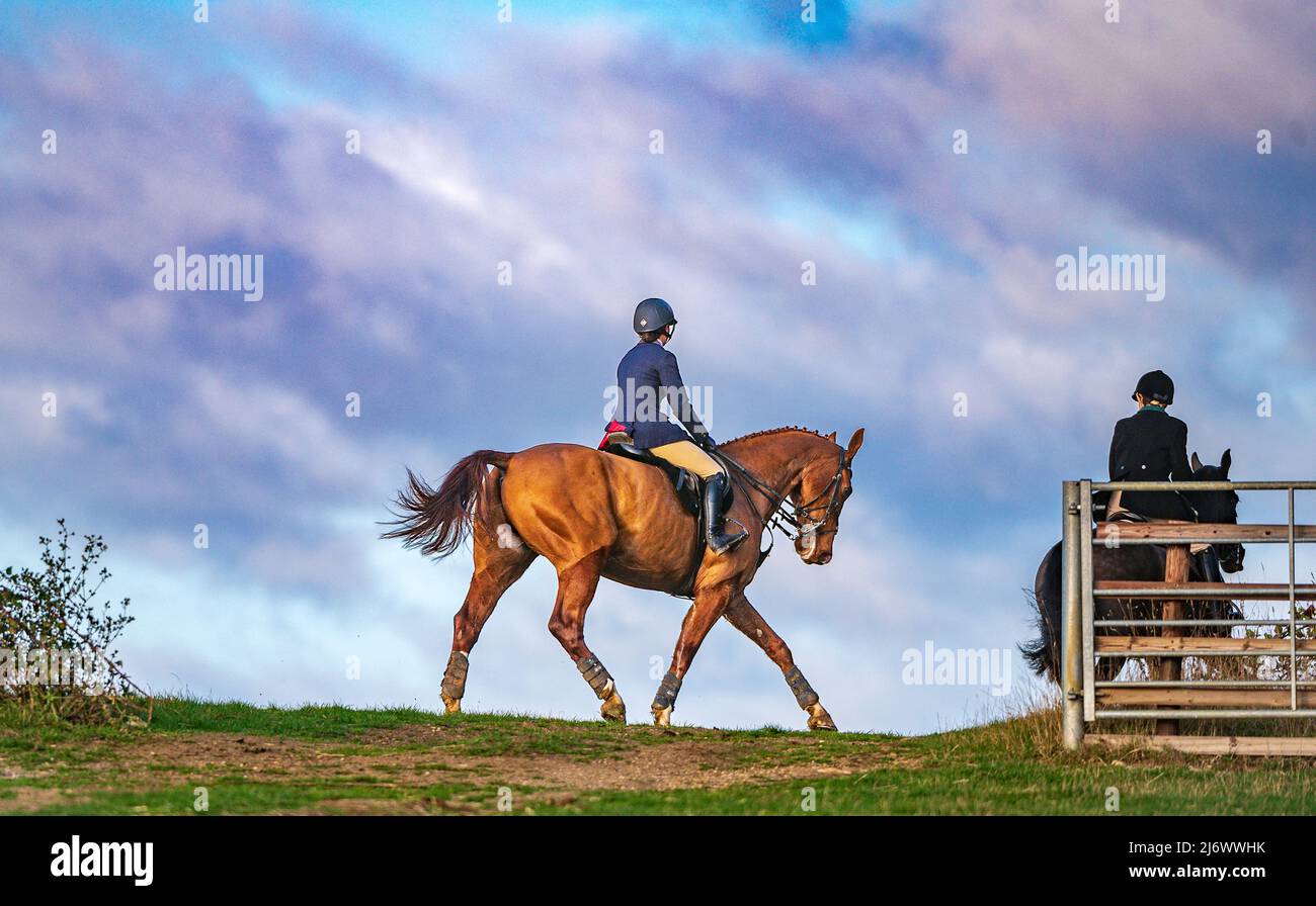 A rider galloping across the skyline on a horse against a stormy sky ...