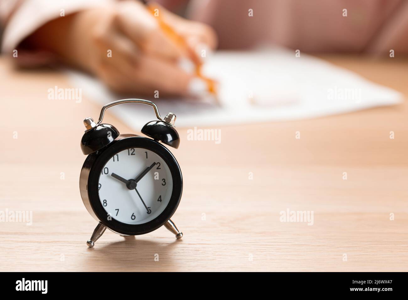 alarm clock with time running out. Students hands to take exams, write ...