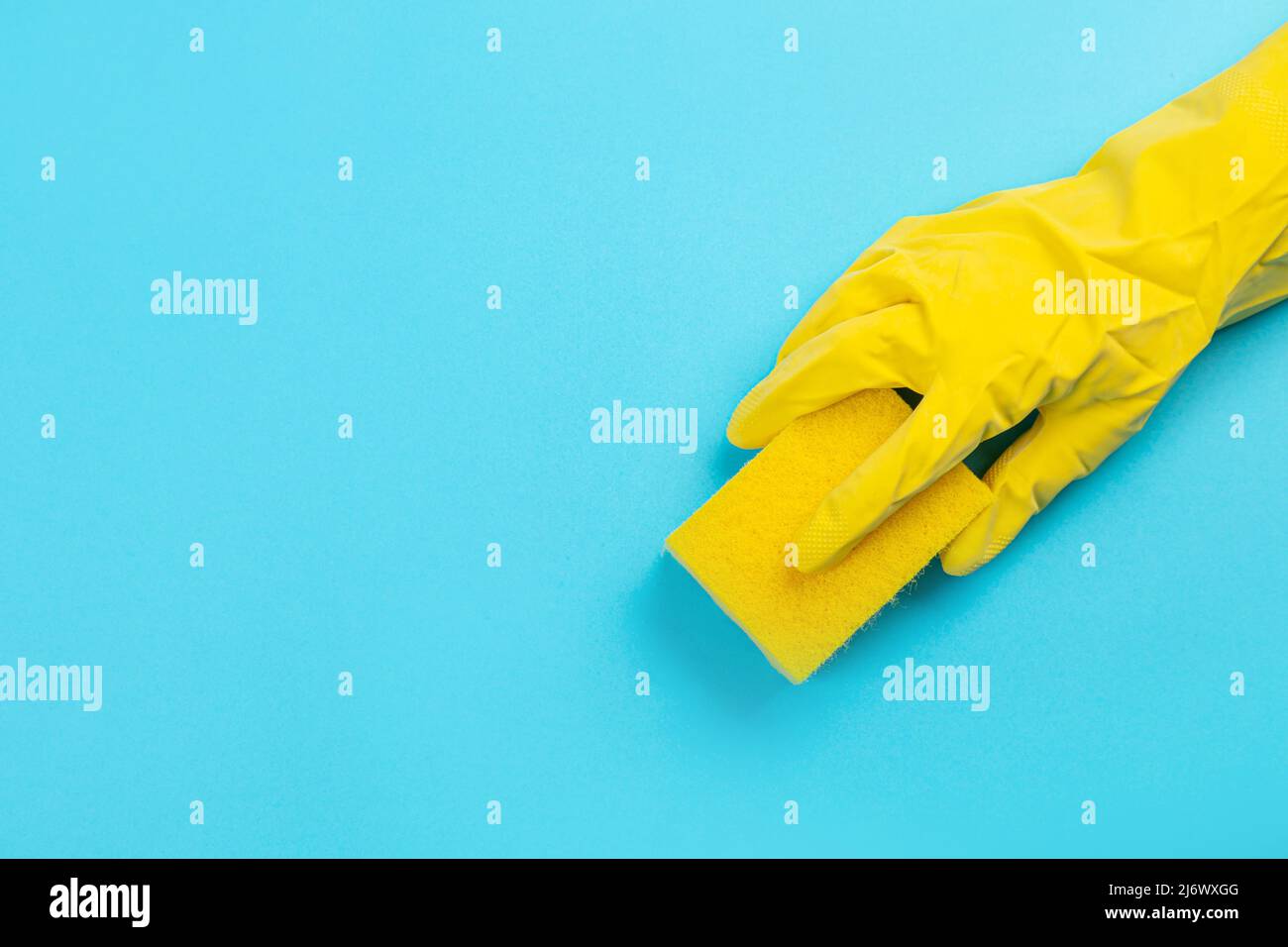 female hand in yellow rubber protective glove with micro fiber yellow ...