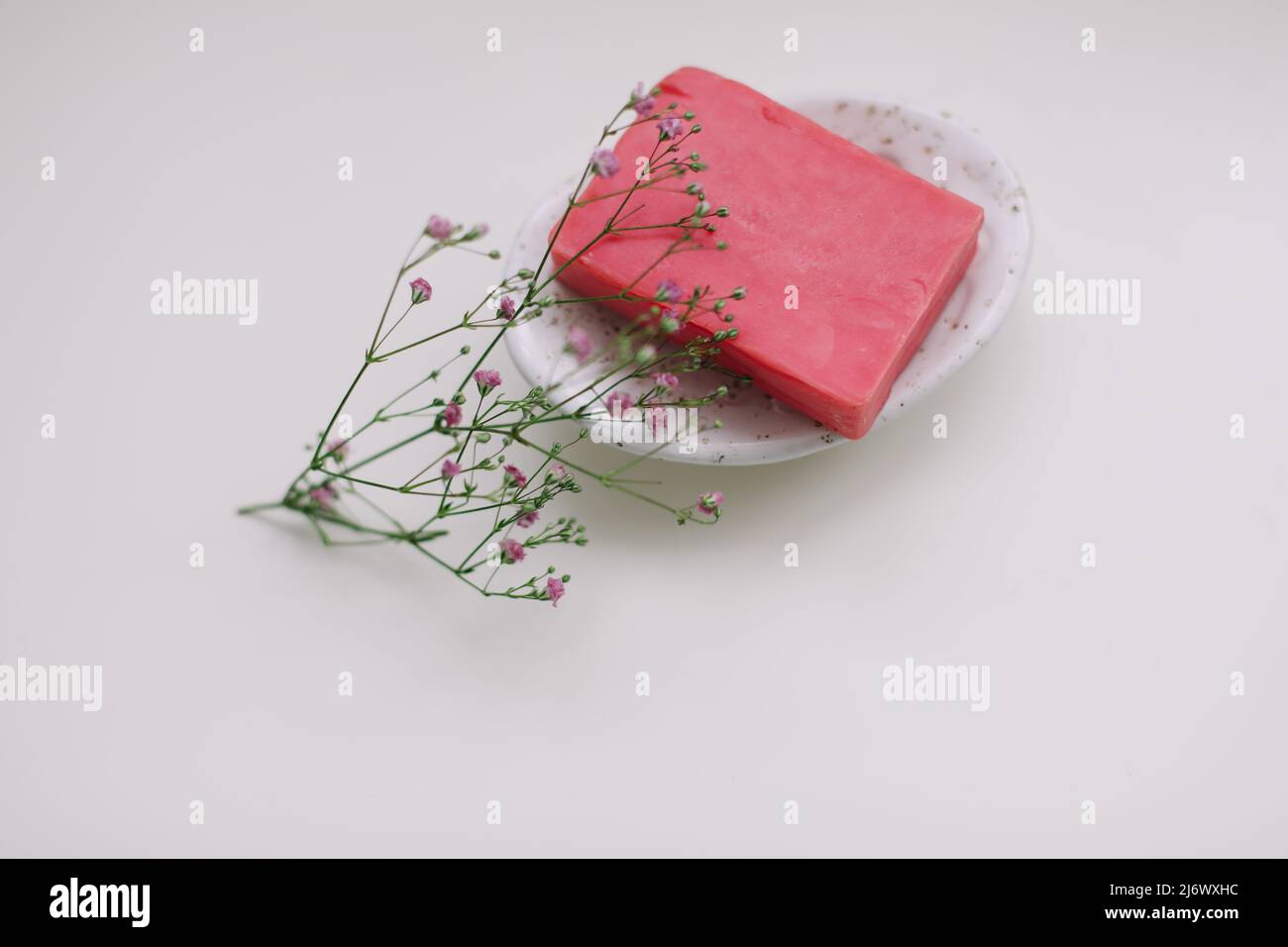 Natural handmade pink soap bar with ceramic soap dish and flowers, spa ...