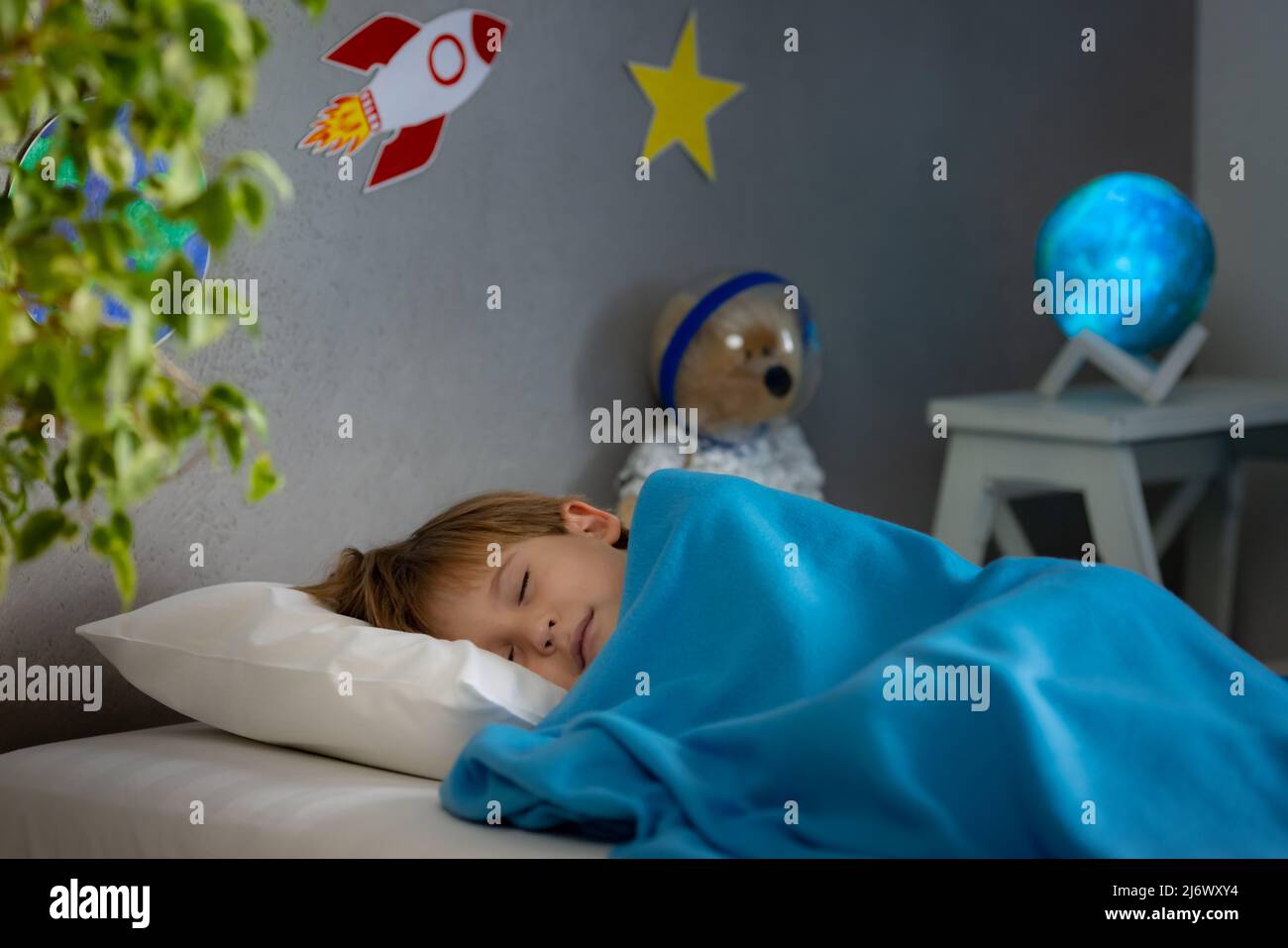 Happy child sleeping with toy rocket and teddy bear. Kid pretend to be ...