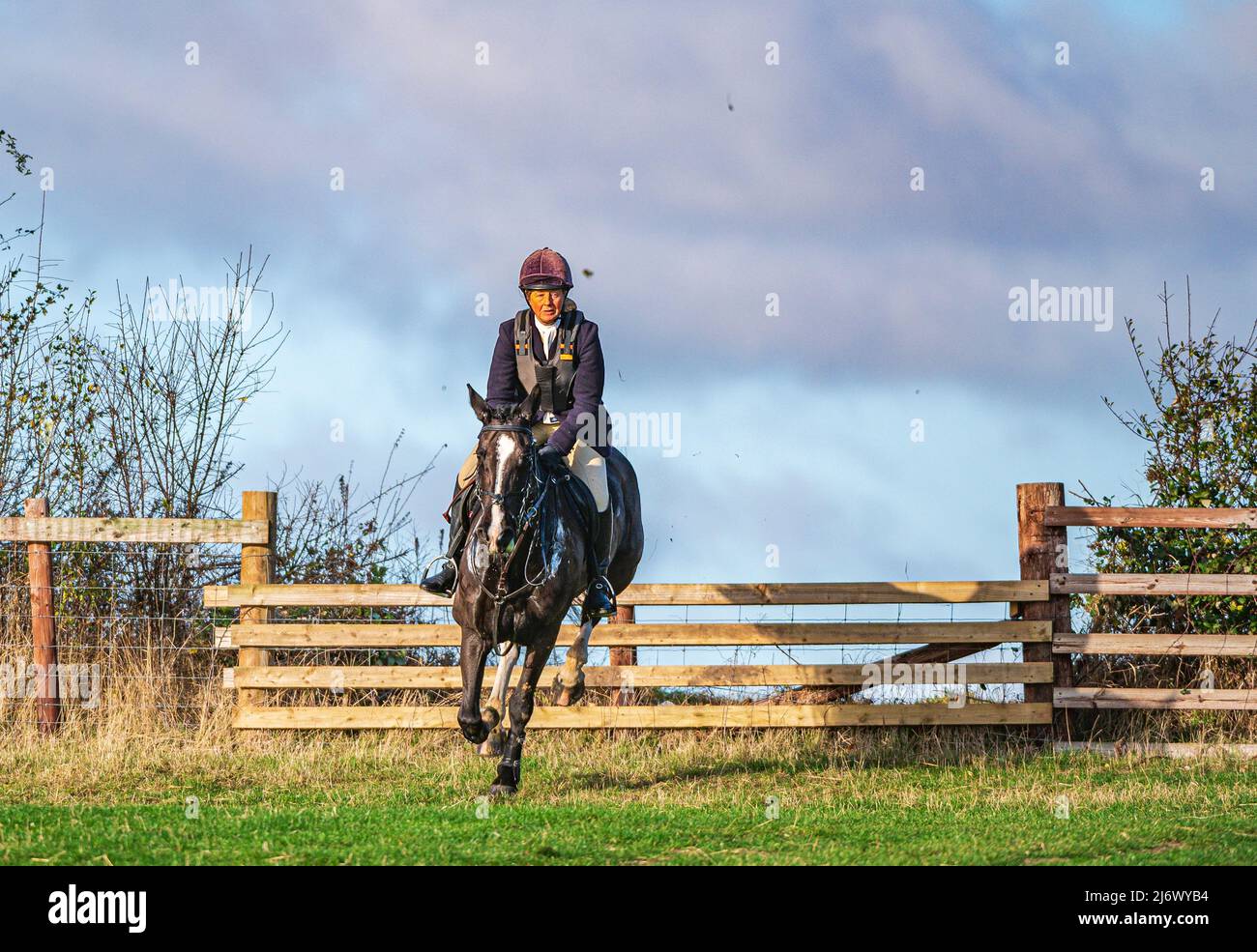 A rider galloping and jumping across the skyline on a horse against a ...