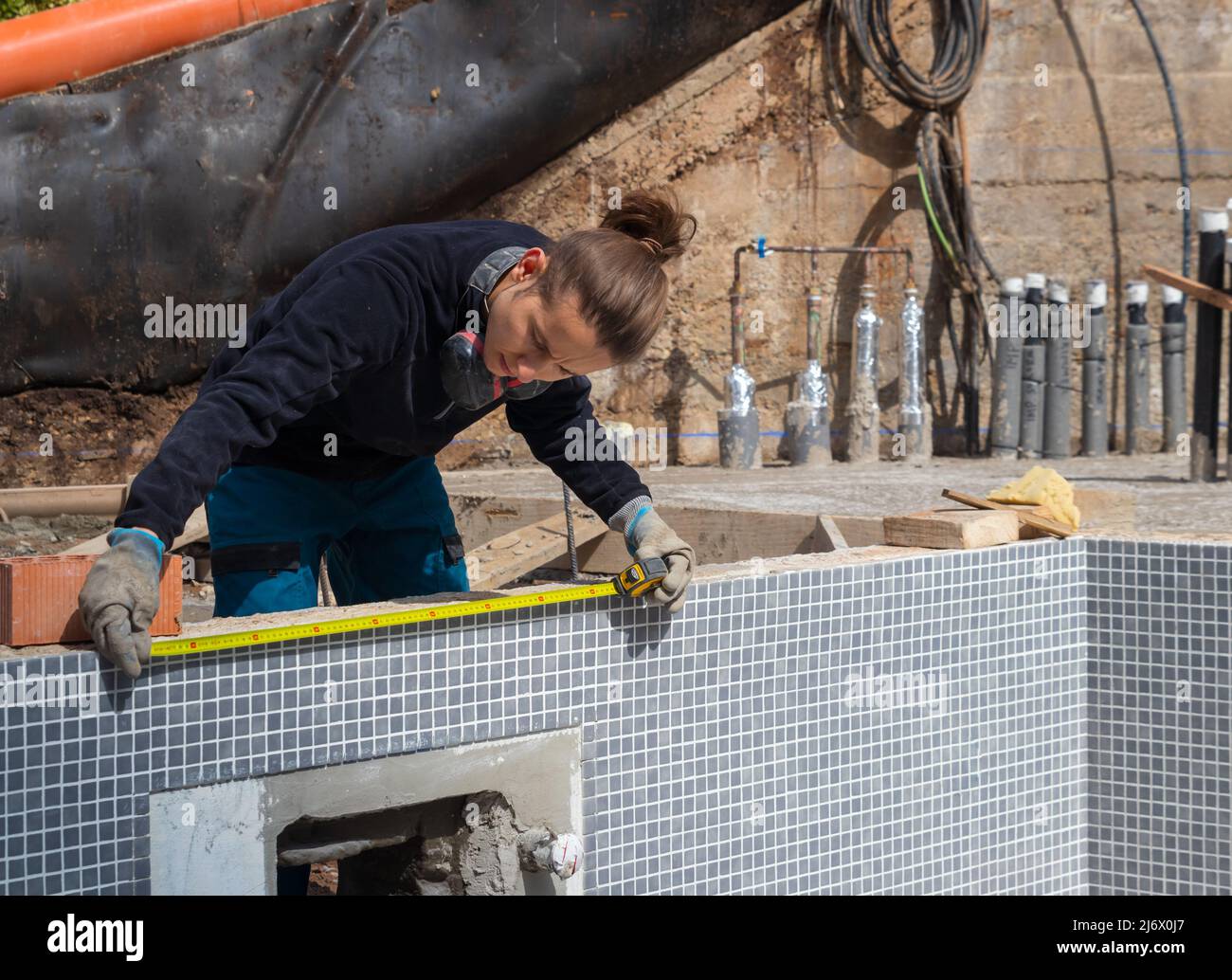 Young working man taking measurements in a swimming pool under ...