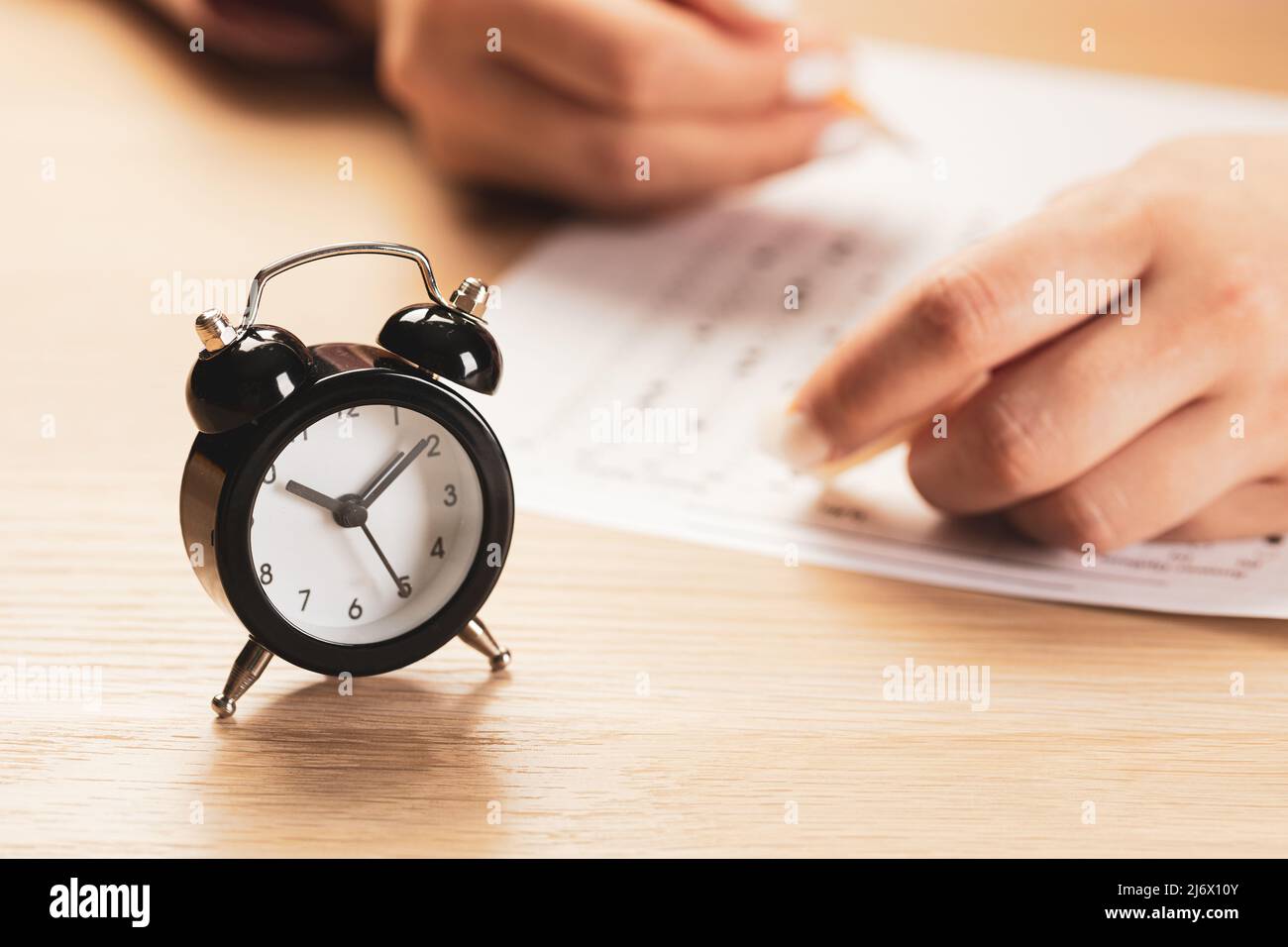alarm clock with time running out. Students hands to take exams, write ...