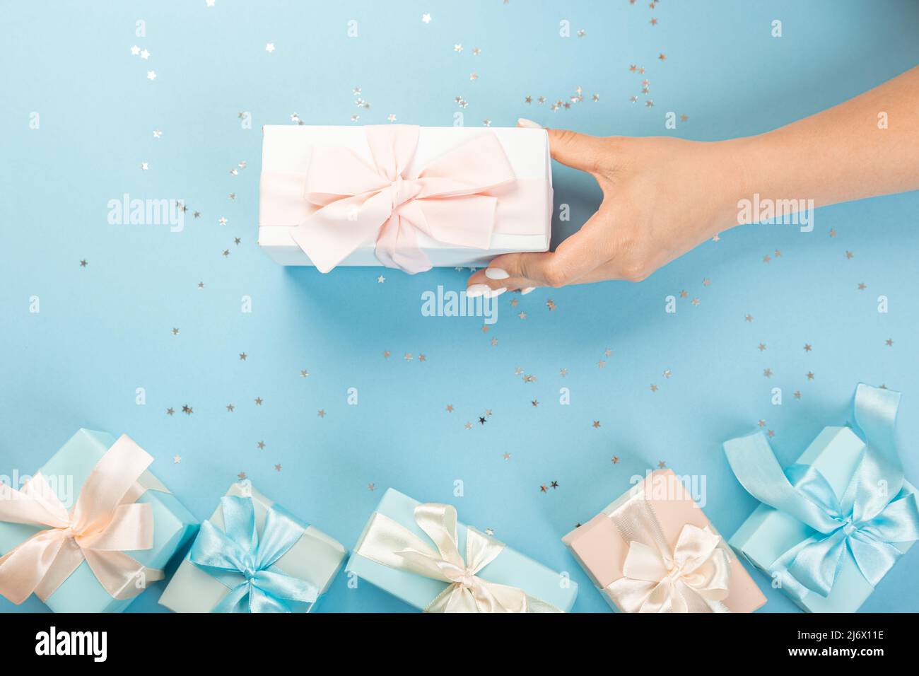 Flat lay of women's hands holding a gift wrapped and decorated with a ...