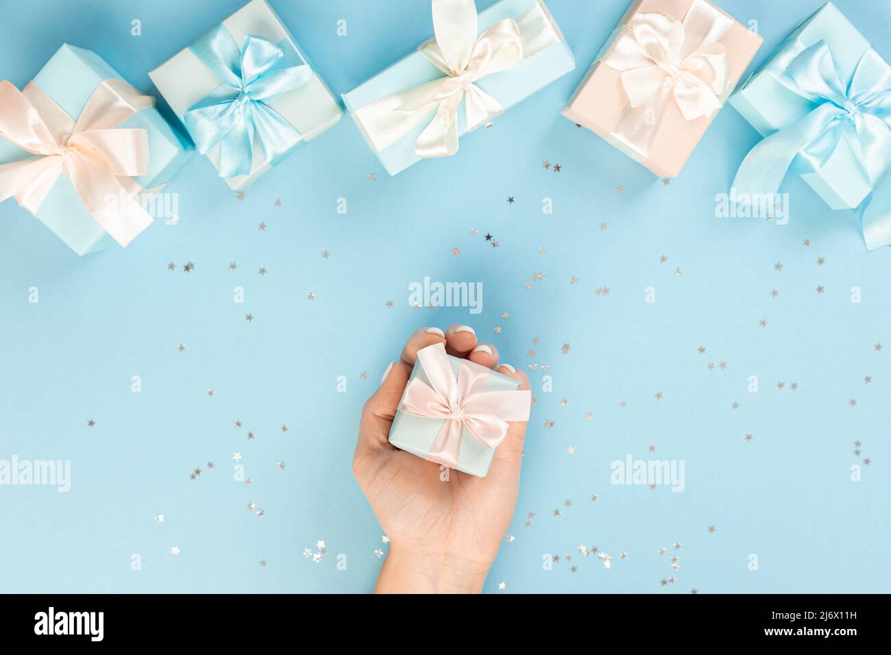 Flat lay of women's hands holding a gift wrapped and decorated with a ...