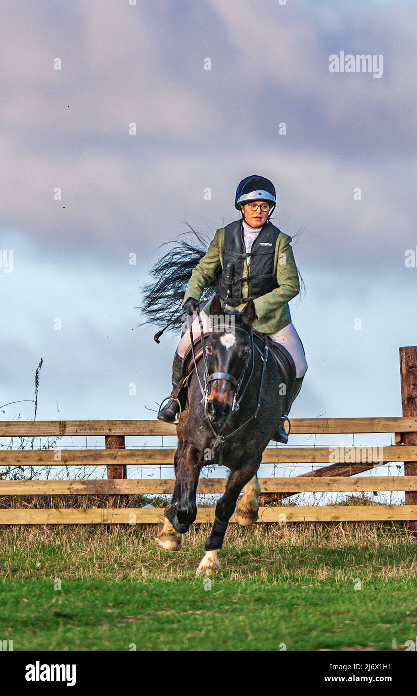 A rider galloping across the skyline on a horse against a stormy sky ...