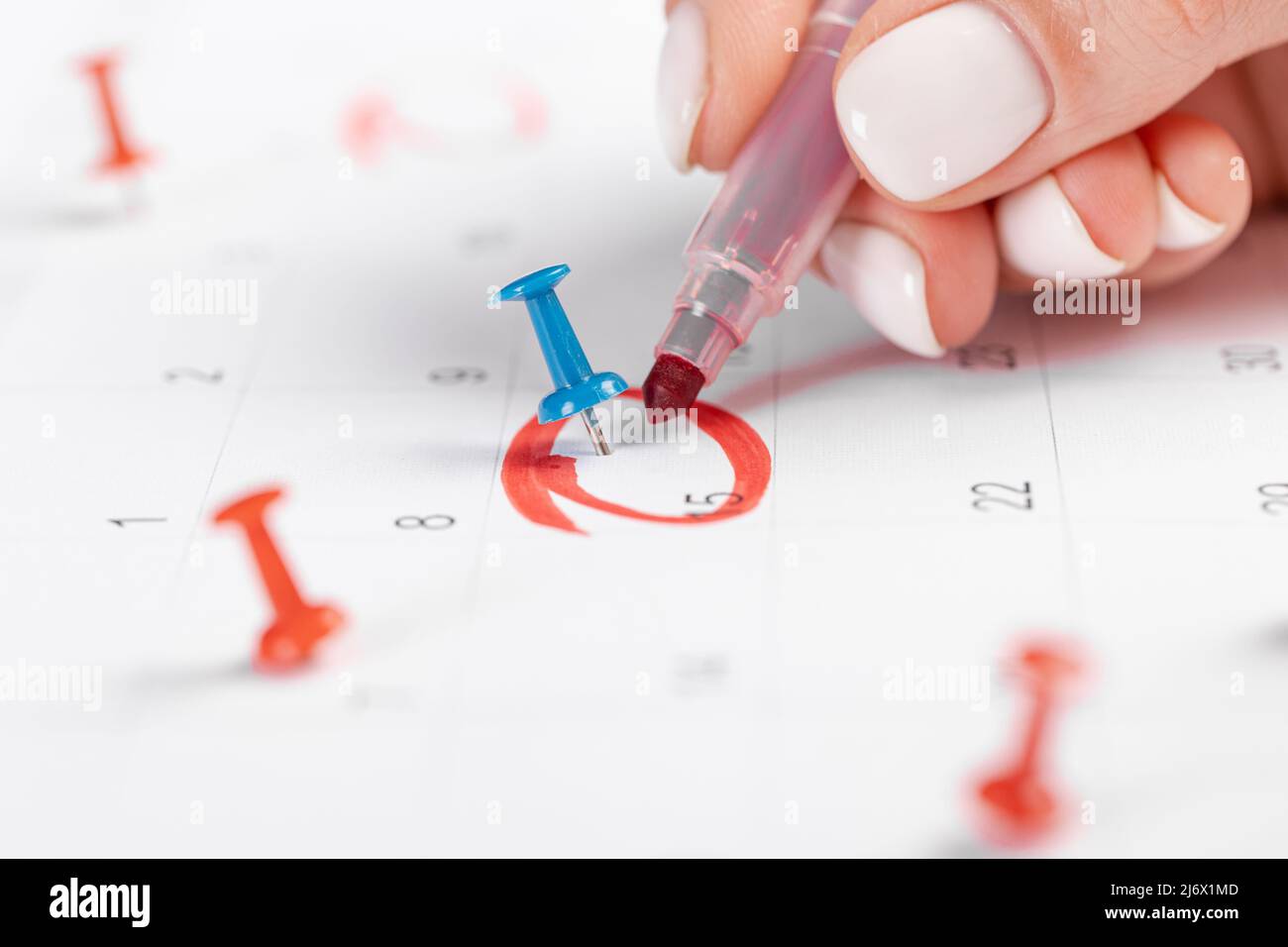female hand marks with a red marker in the calendar notes an important ...