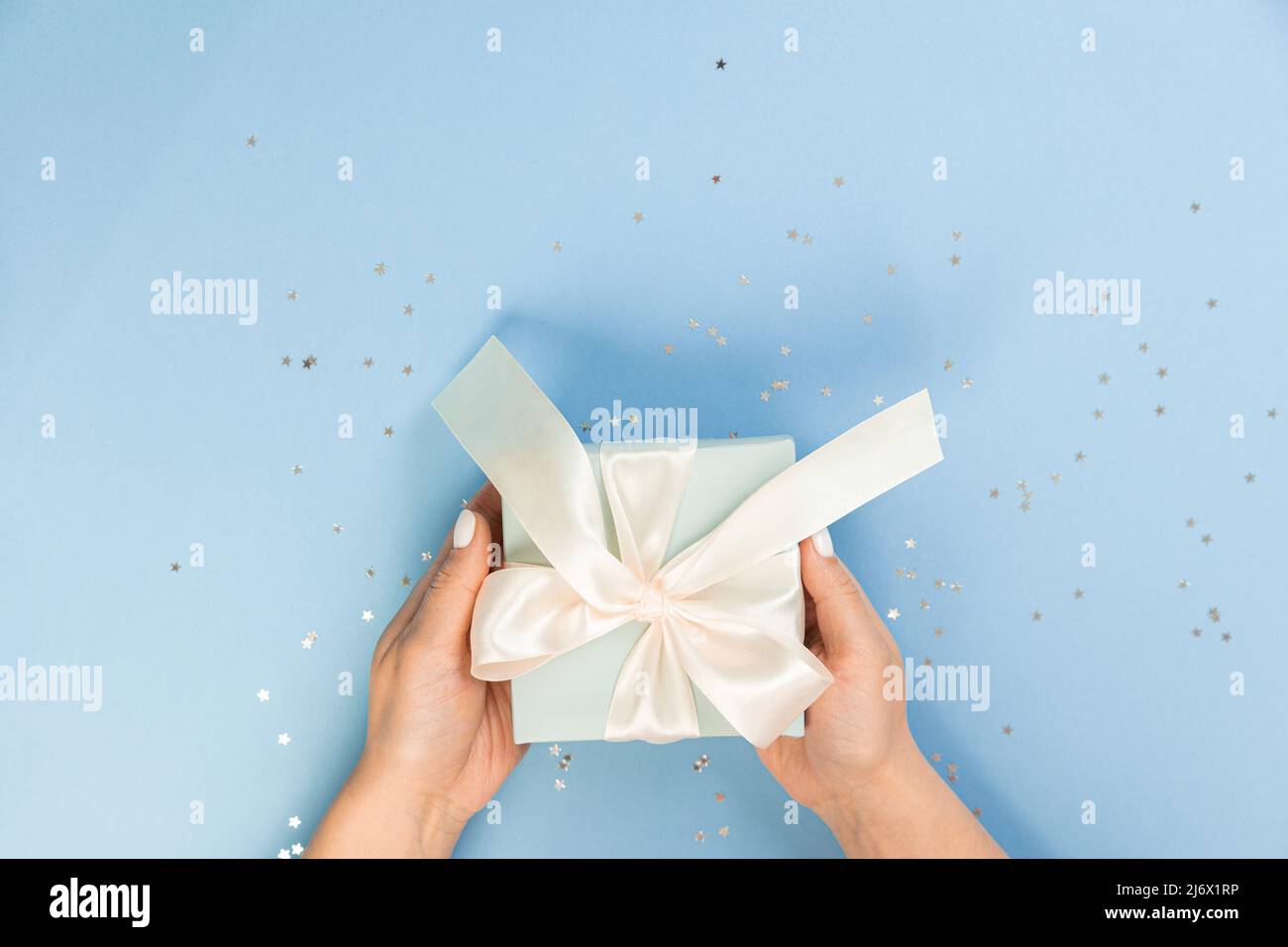 Flat lay of women's hands holding a gift wrapped and decorated with a ...