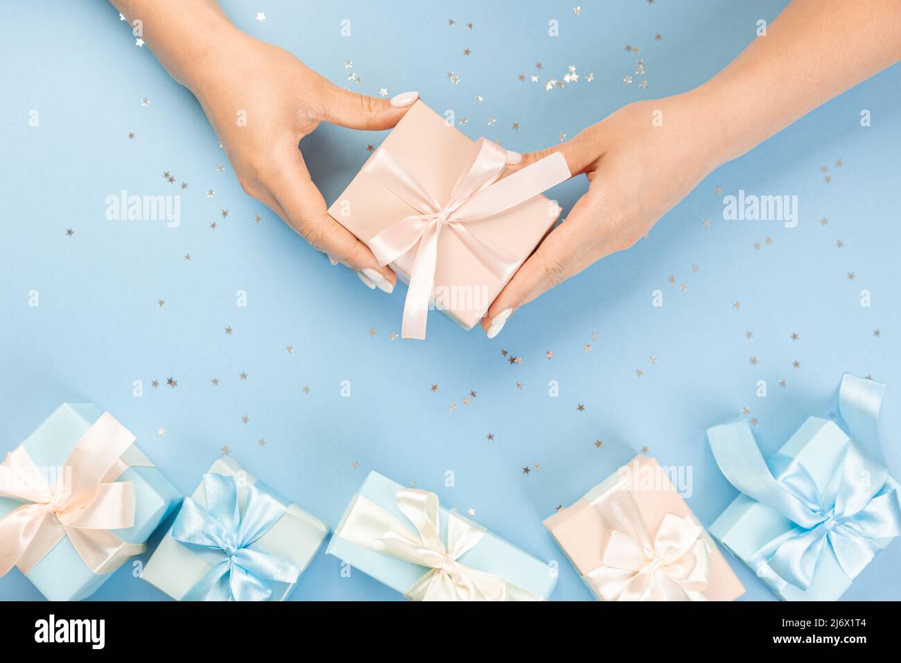 Flat lay of women's hands holding a gift wrapped and decorated with a ...