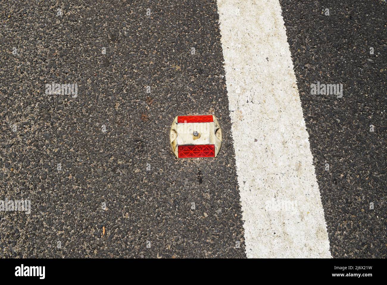 Metal Road stud with Red reflector on asphalt road with white painted ...