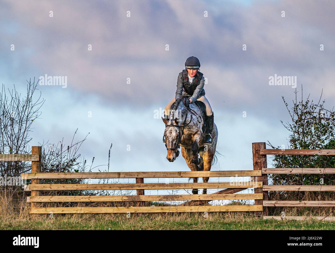 A rider galloping across the skyline on a horse against a stormy sky ...
