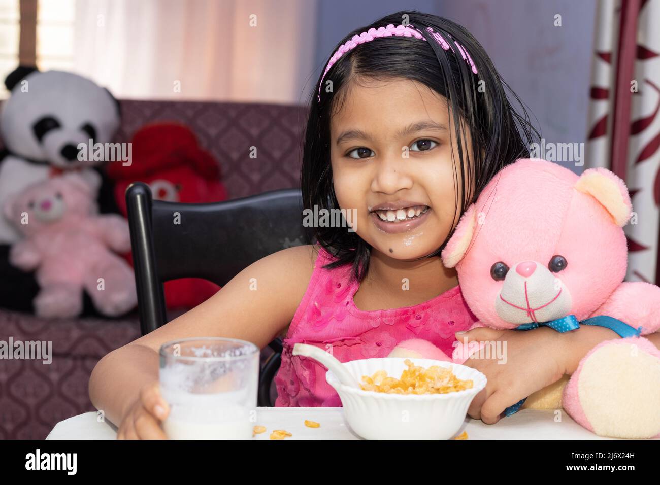 An Indian girl child eating cereal with milk with smiling face and ...